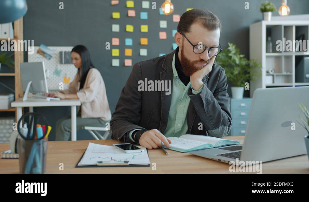 Tired guy sleeping in workplace then working with computer, coworker ...