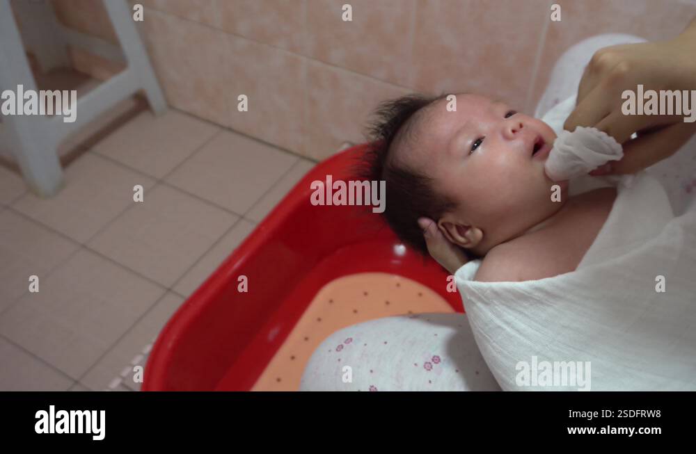 A Chinese Asian mother wipe face of adorable baby using clean ...