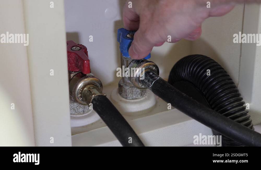 Plumber turning off cold water supply shut-off valve for washing ...