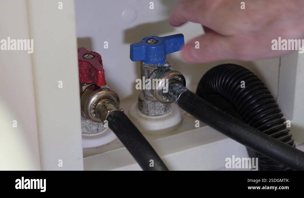 Plumber turning on cold water supply shut-off valve for clothes washing ...