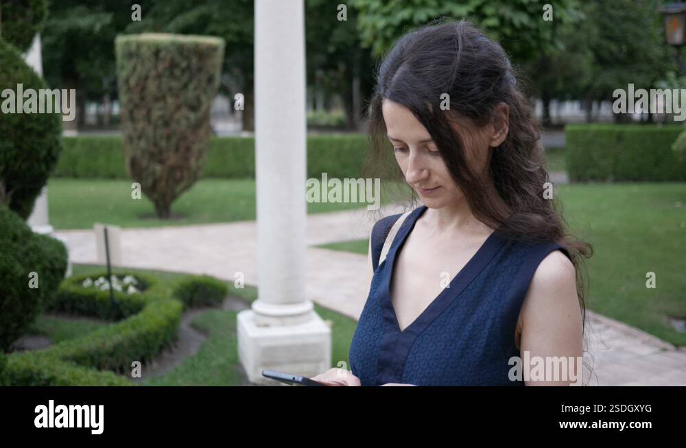 young beautiful brunette woman in Park summer with phone in hand, calls ...