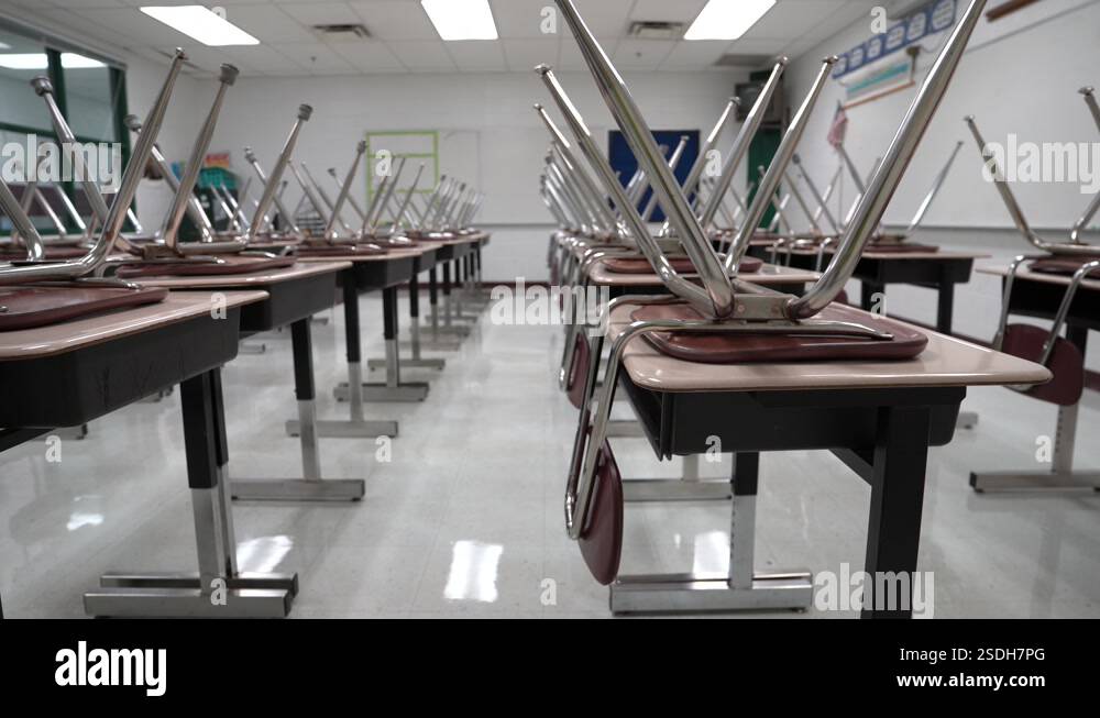 Slider shot to the left of empty school classroom with chairs on the ...
