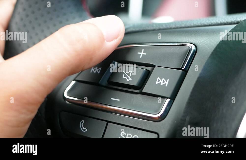 Finger pressing the audio control buttons on the steering wheel when ...
