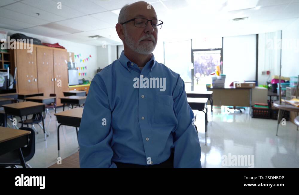 Wide angle view of sad, depressed teacher in empty, dark classroom ...