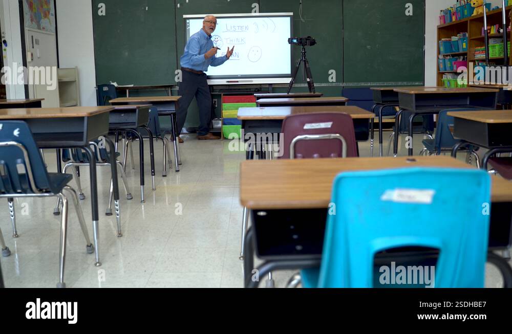 Male teacher using an interactive whiteboard in an empty classroom ...