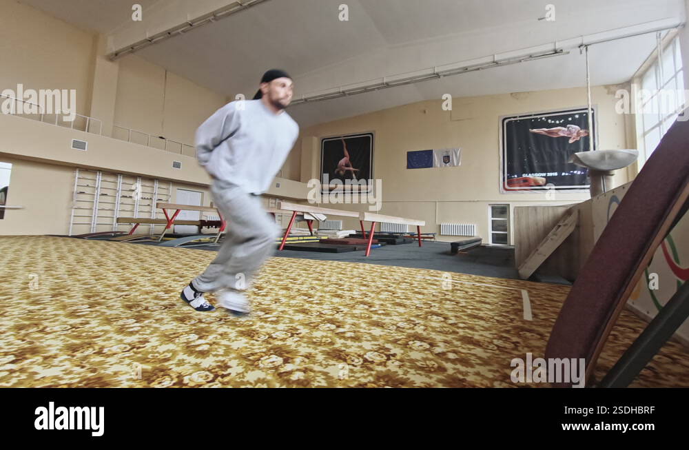 Sportsman with hands behind back running and doing back flip during ...