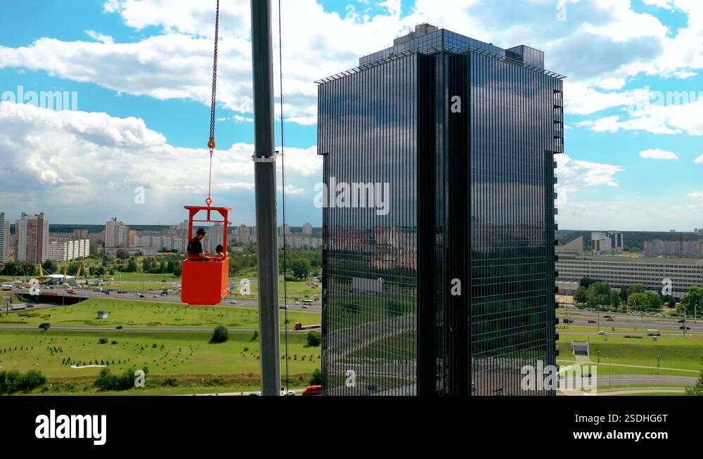 Two construction workers in the building cradle of a mobile crane ...