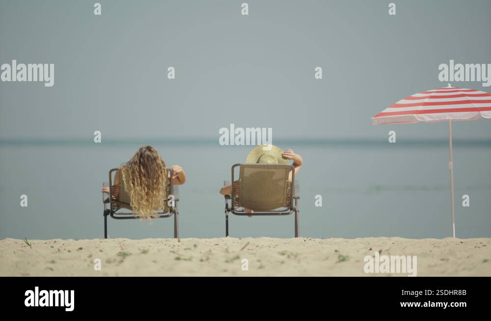 Two gorgeous relaxed young women lying on sun loungers and sunbathing ...