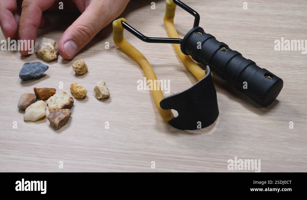 Man hand take stone with slingshot small hand-powered projectile weapon ...