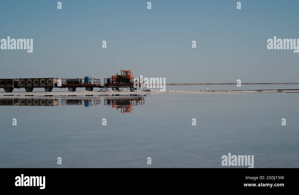 An old train travels on a railway laid in the water across a salt lake ...