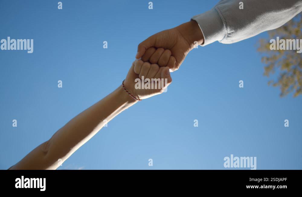 Bottom view of friends fist bumping greeting each other over blue ...
