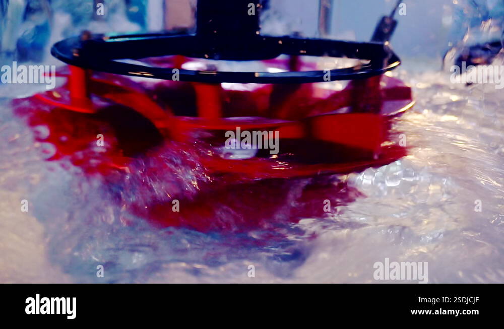 powerful turbine rotates in water in a transparent glass container ...