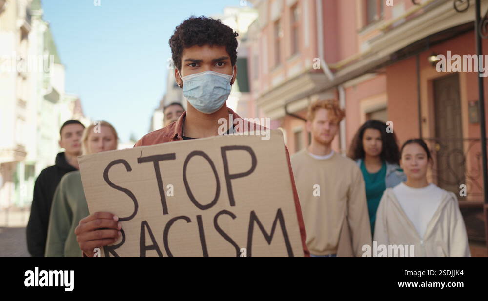 Mixed race man leader at the protest showing poster with Stop Racism ...