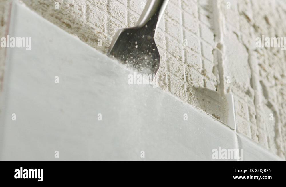 Slow motion of a rotary hammer breaking ceramic tiles off a wall Stock ...