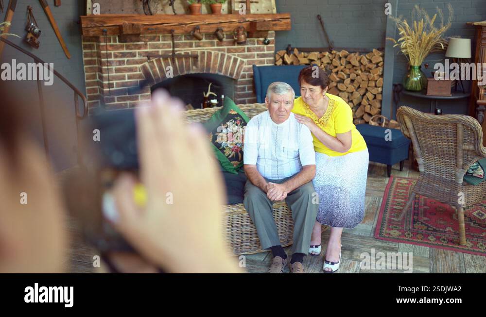 elderly couple in chair in country house by fireplace. backstage photo ...