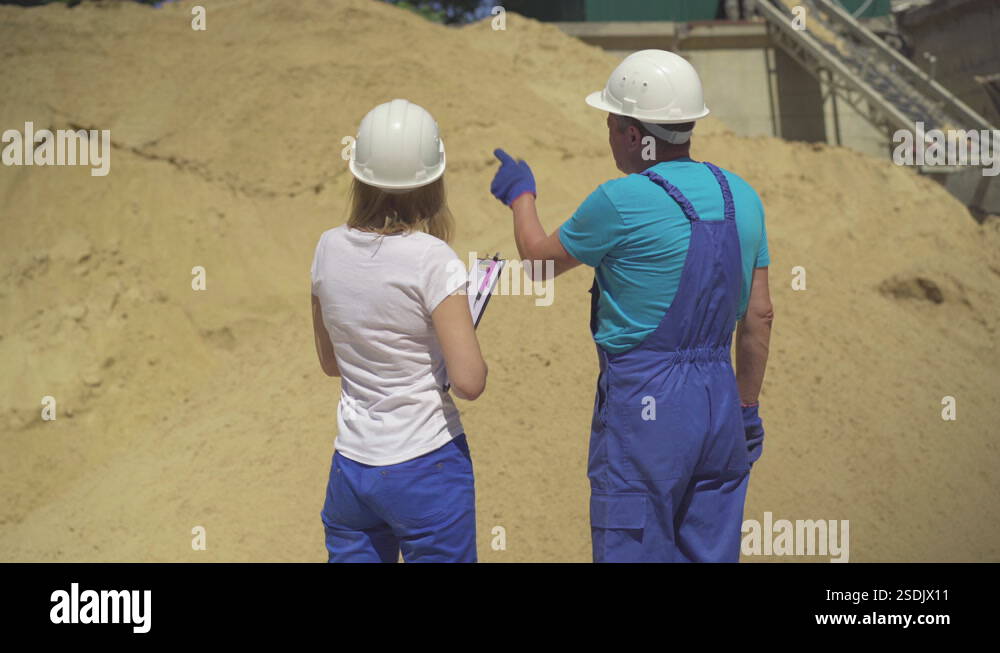 Back view of male worker and female inspector standing in front of ...