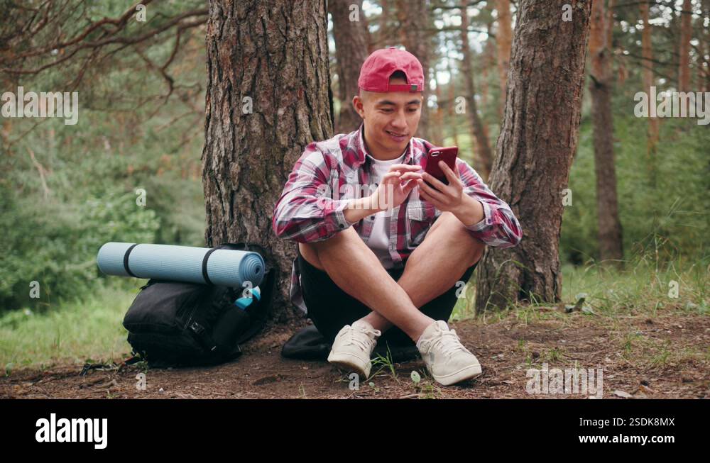 Asian Hipster Man sending voice messages with mobile phone at park ...