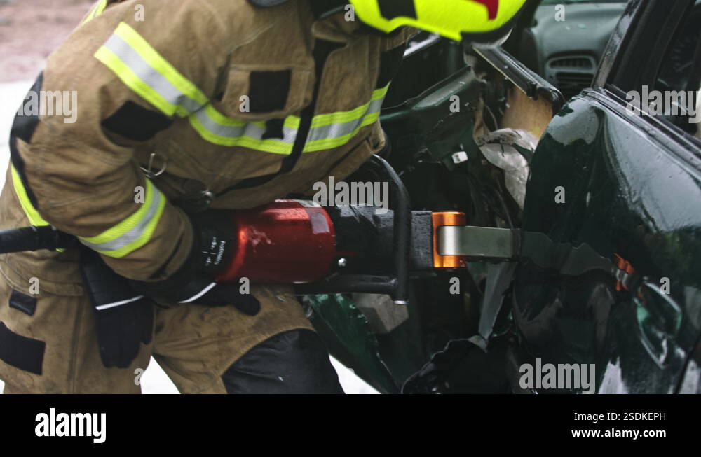 Firefighter using jaws of life to extricate trapped victim from the car ...