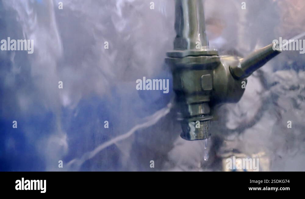 Rotating metal nozzle washes a transparent container with a stream of ...