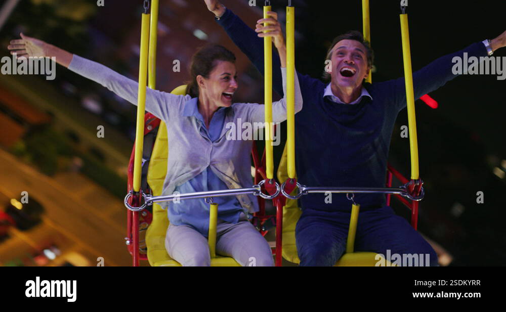 Happy excited couple have fun to ride chain swing carousel in luna park at night Stock Video ...