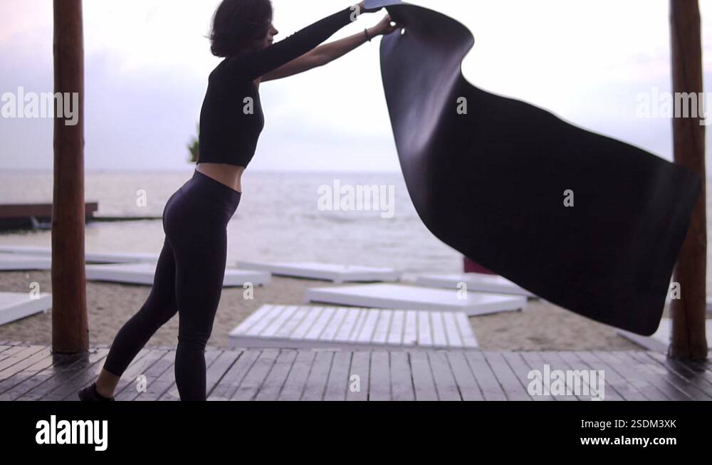 Caucasian woman unfolding a yoga mat on a wooden floor close to the ...