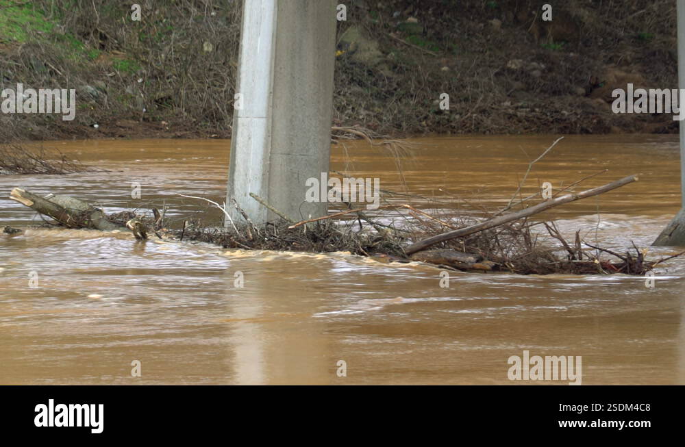 debris from flood abuts bridge pile in muddy water Stock Video Footage ...