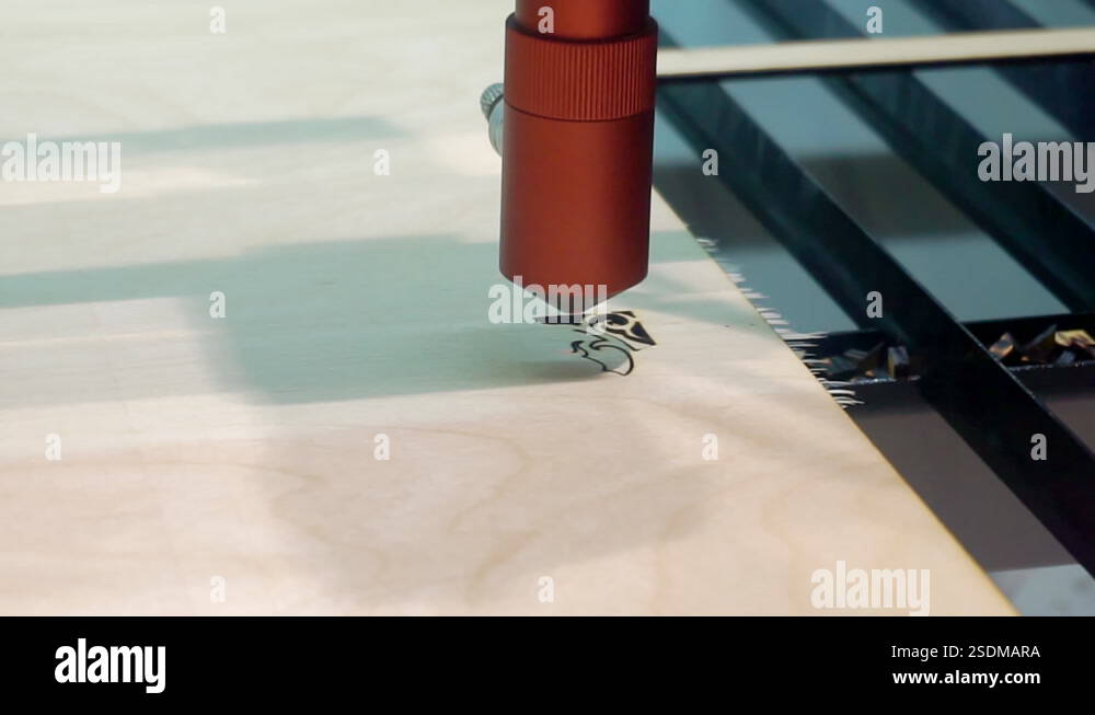 The laser beam passes through the plywood, cuts out a drawing or ...