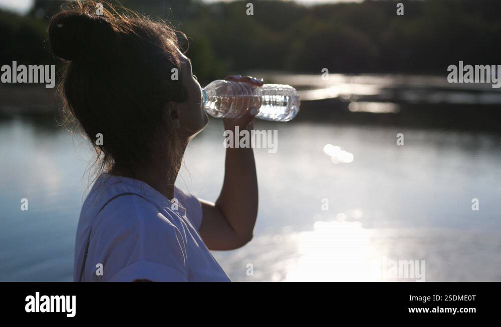 Girl quench their thirst on a hot sunny day after a jog, drink water ...