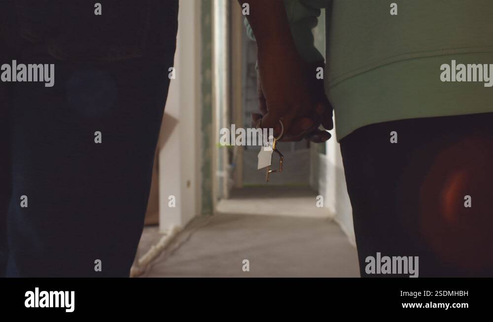 Close-up of keys in hands of african couple walking in new apartment ...