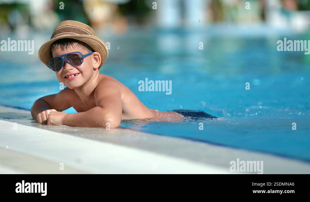 Trendy male kid splashing in swimming pool having fun and positive ...