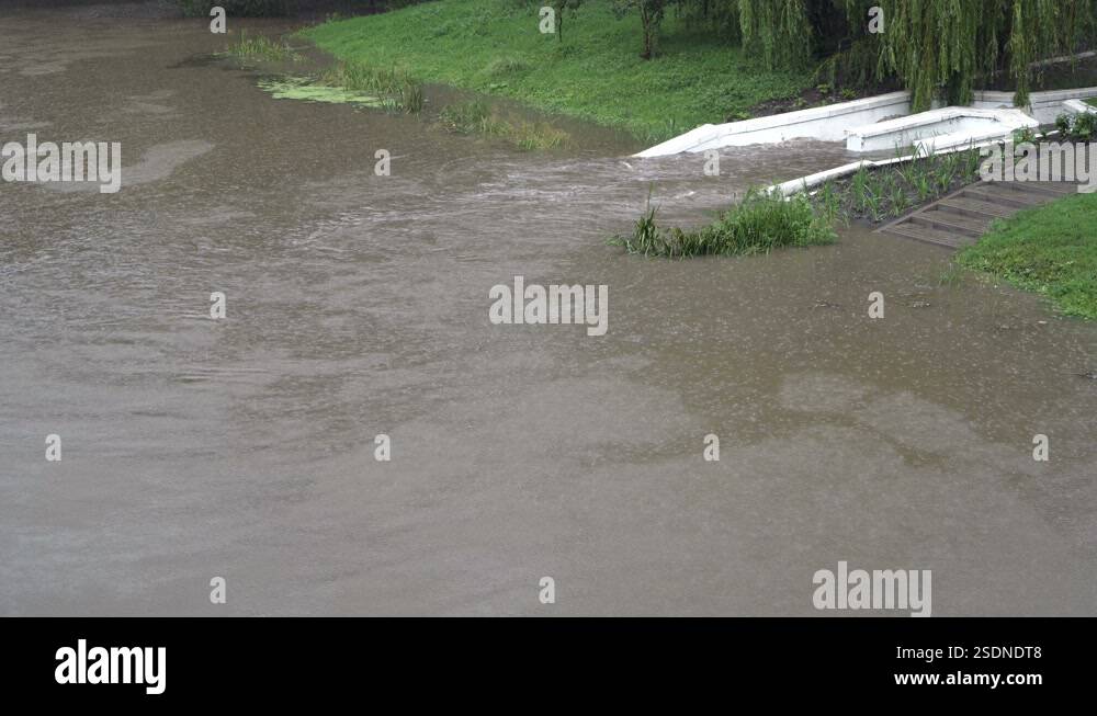 Heavy rain over the surface of the river in the city Park. View of the ...