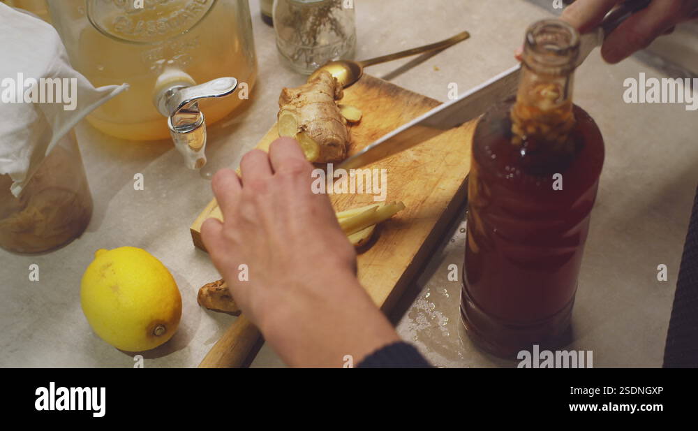 Healthy beverage kombucha.Female hands slicing fresh ginger in kitchen ...