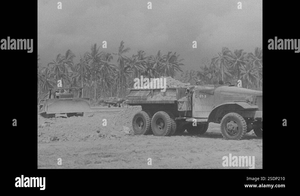 1940s Pacific Islands: Bulldozer and dumptruck move dirt on beach ...