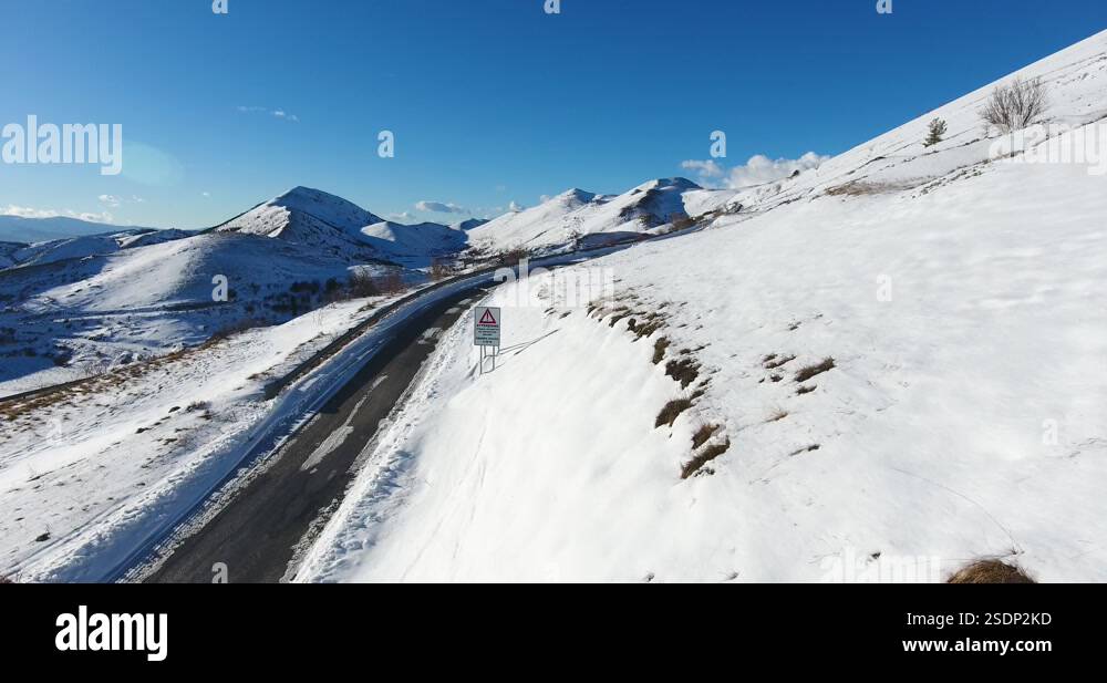 Aerial view over a icy road sign and a slippery route in the snowy ...
