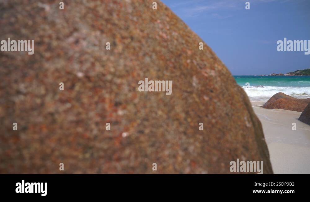 Slow linear realtime dolly past granite rock showing beach and waves in ...