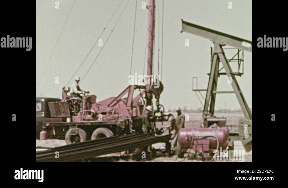 1960s: Men use crane to lift pipe. Man sit at desk and looks through ...