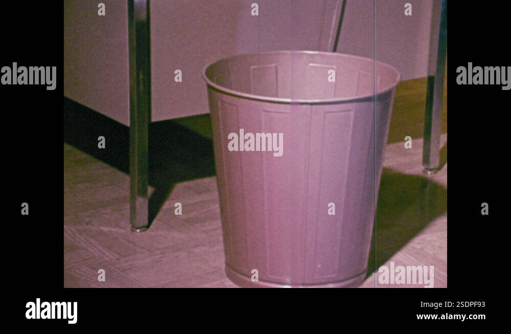 1970s: Office. Trash can slides close to desk. Electrical cord crosses ...