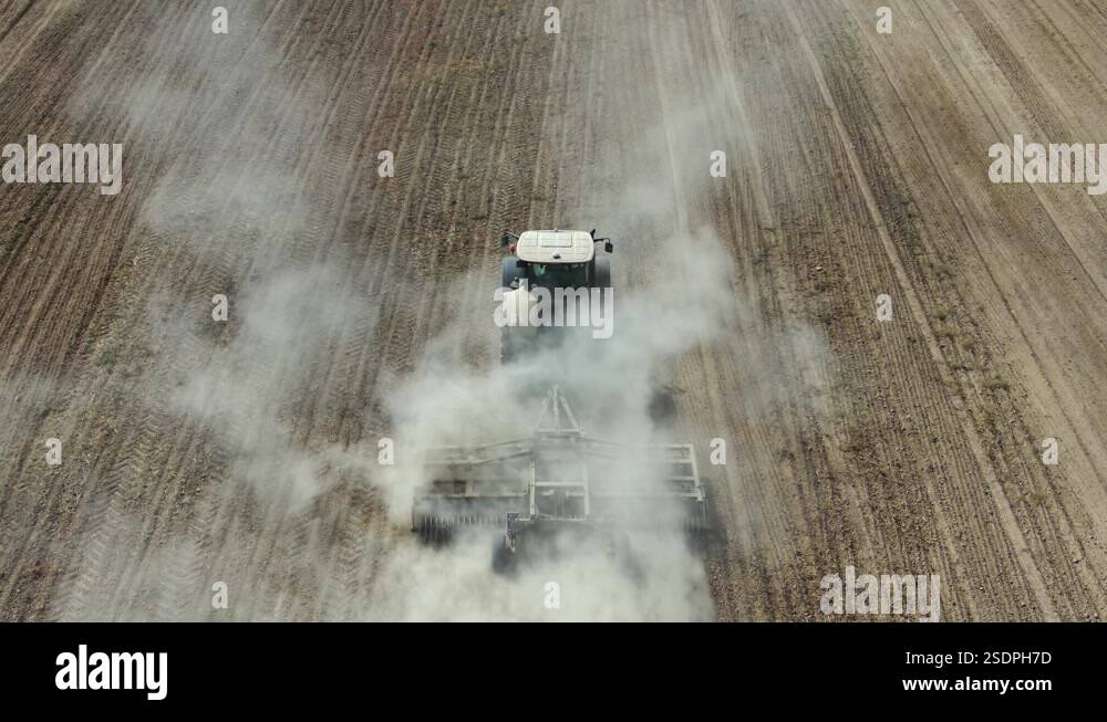 Puffy Smoke From A Tractor With A Seeder Sowing In A Plowed Field In ...