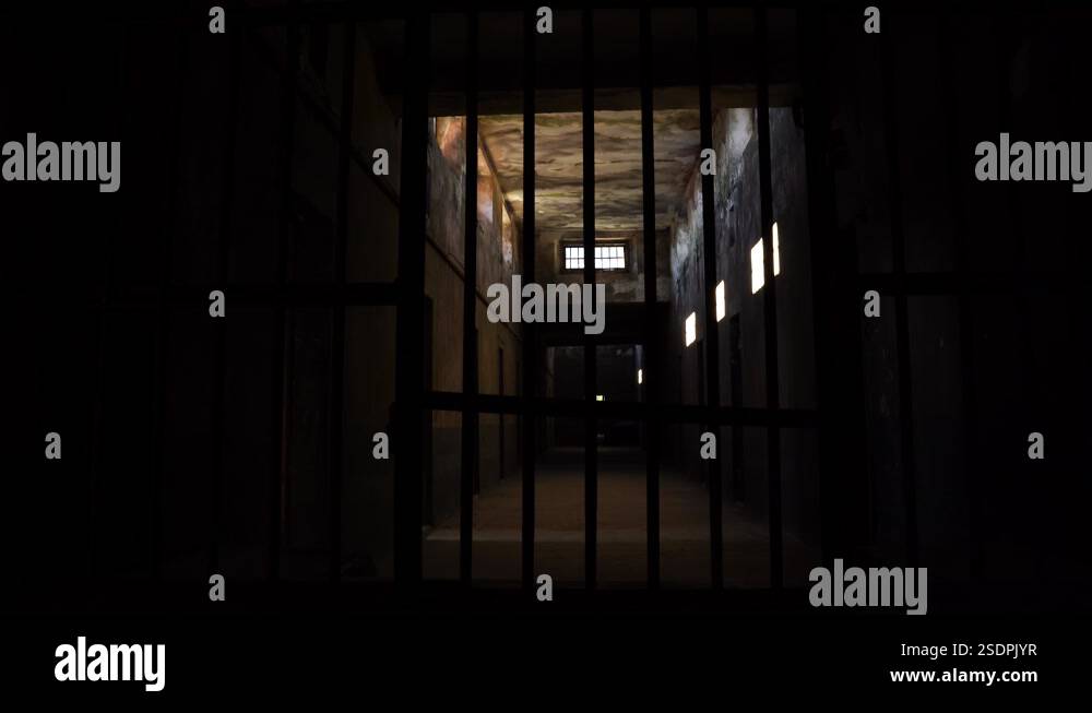 Iron gate of prison with dirty walls and small windows, dark jail ...