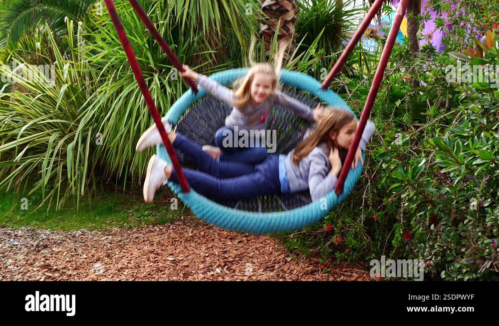 two girls riding on a large round swing in the park. fun for children in nature Stock Video ...