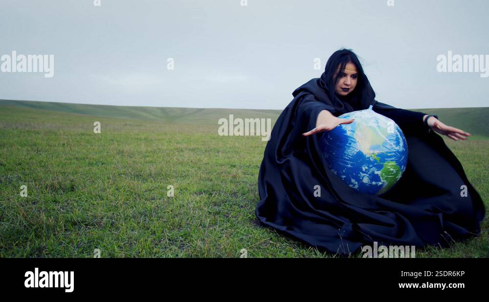 Witch with a long black cape is conjuring, sitting with the Earth, evil, 4k Stock Video Footage ...