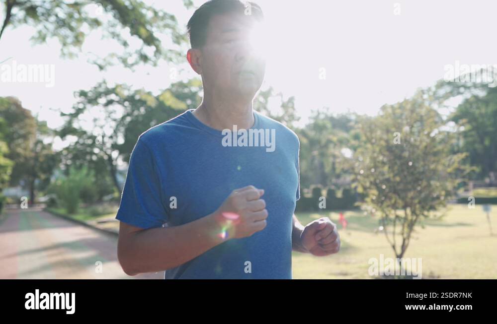 Asian senior man running inside the running track at the park on a ...
