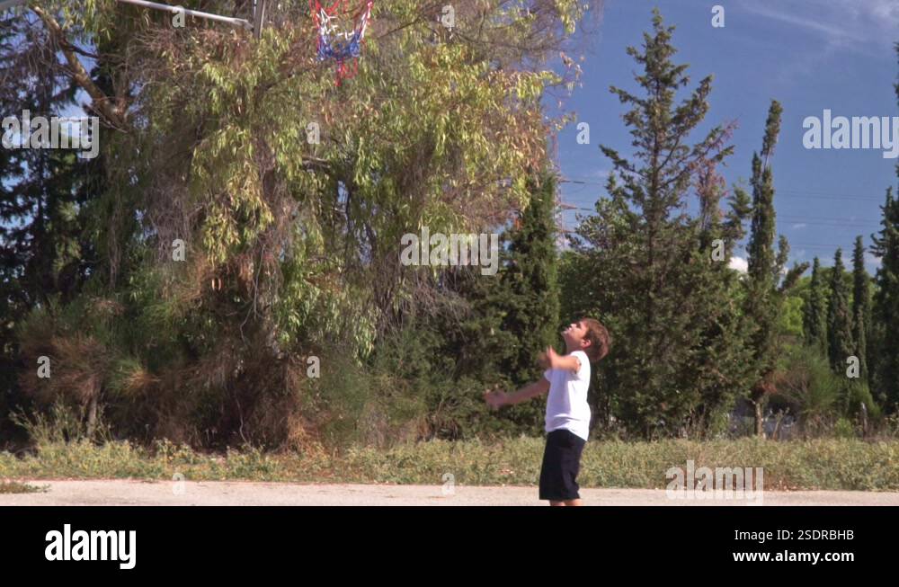 Caucasian boy, takes a shot behind the hoop , at alley basketball court ...