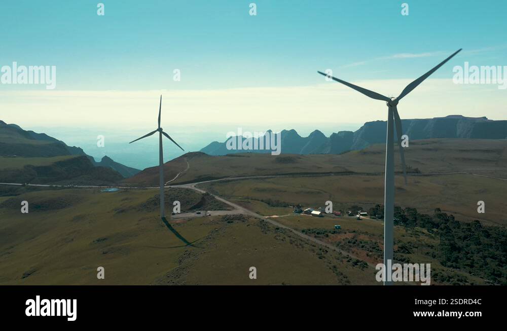 Two wind turbine generators on top of a plateau near mountains and ...