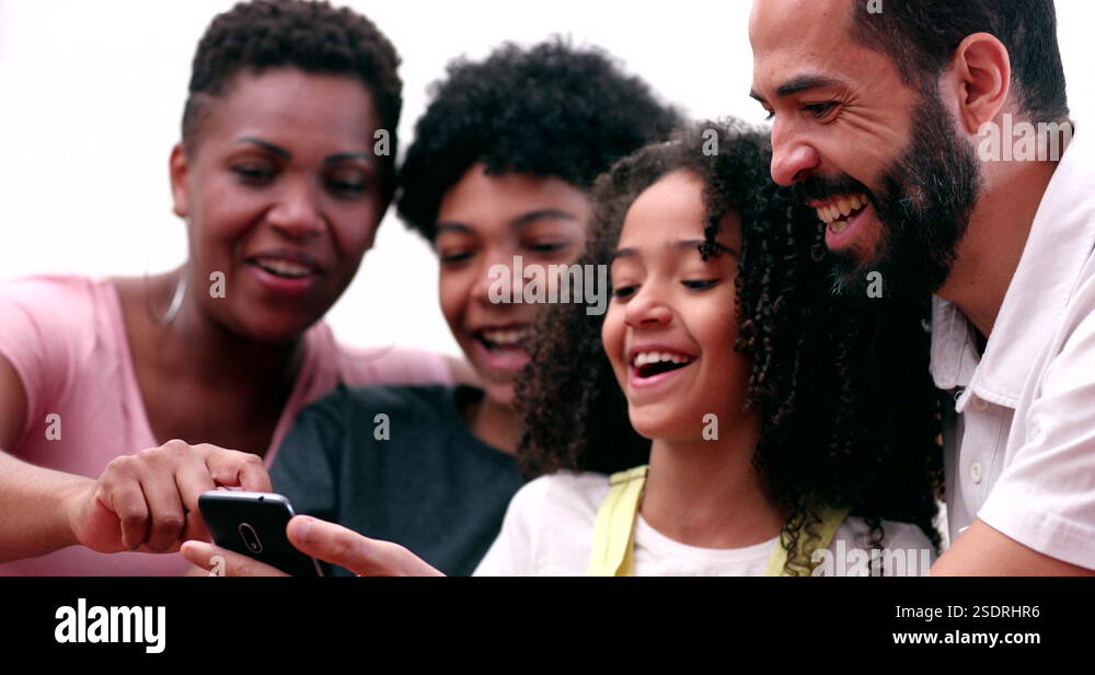 Happy multiracial family laughing and smiling together looking at phone ...