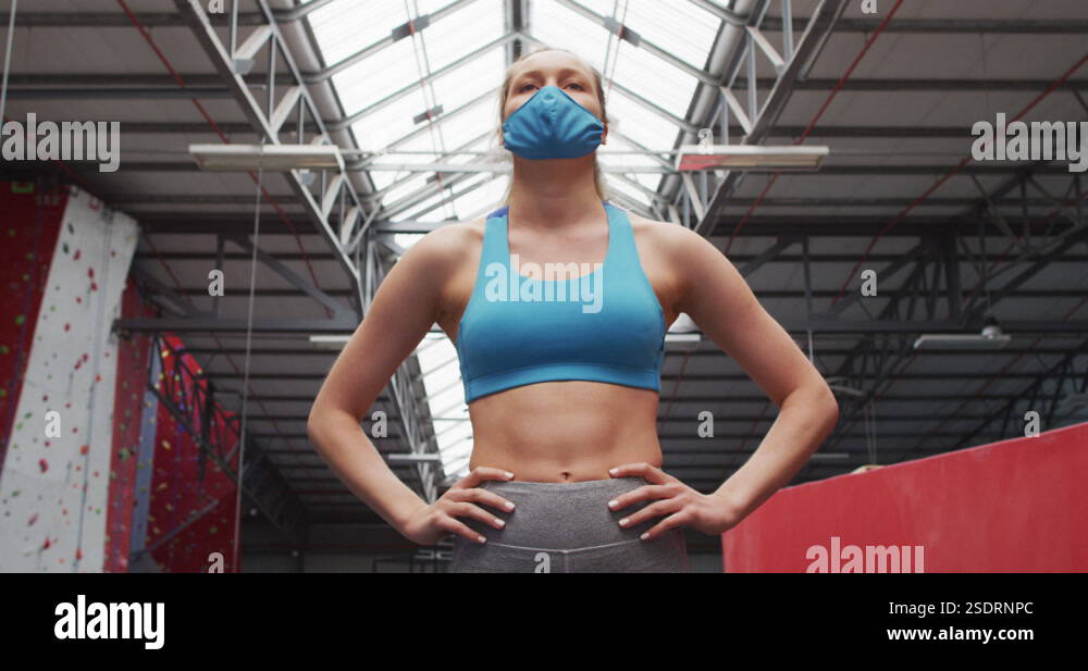 Fit caucasian woman wearing face mask standing with hands on her hips ...