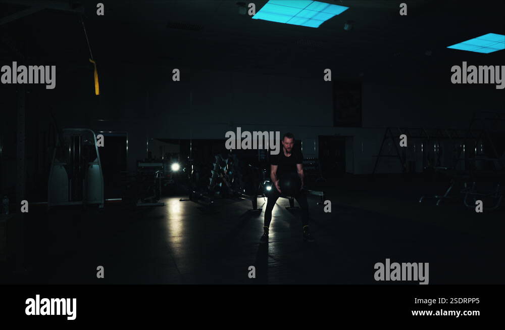 Strong man throwing heavy ball in dark gym Stock Video Footage - Alamy