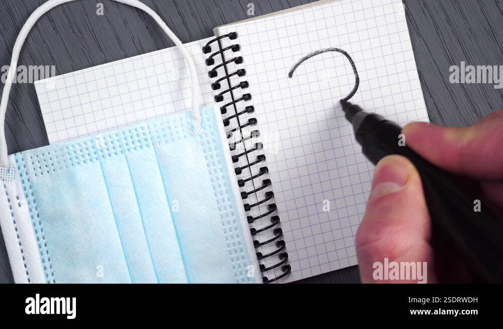 Hand writes in black marker a question mark in an open notebook with a ...