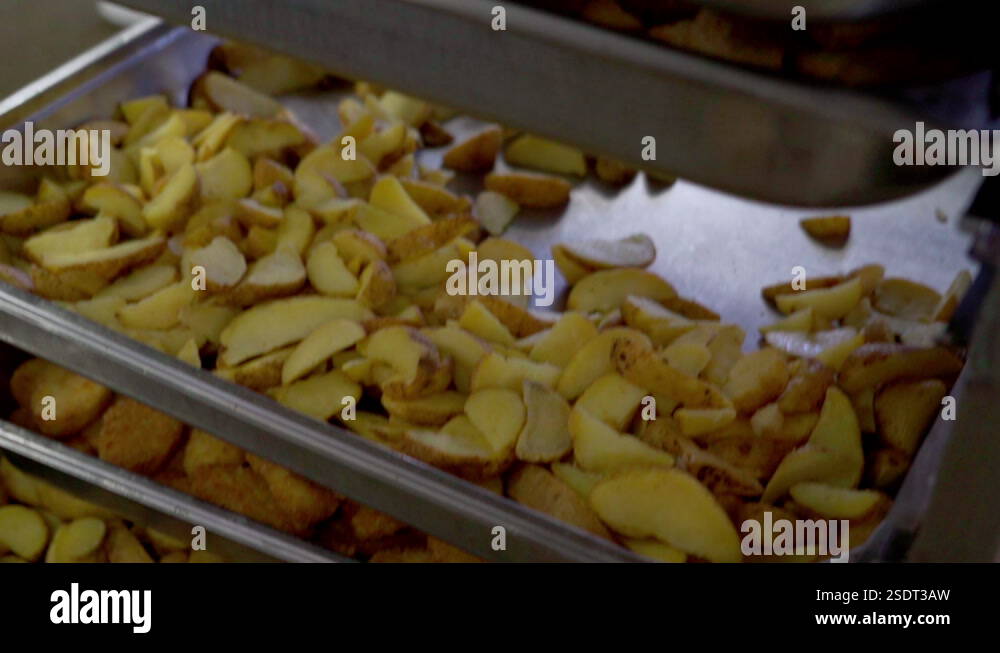 Fried potatoes and nuggets in metal plates on industrial rack close up ...