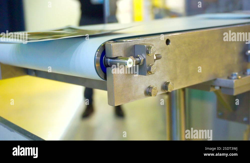 finished goods packed in a bag move along the conveyor belt and fall ...